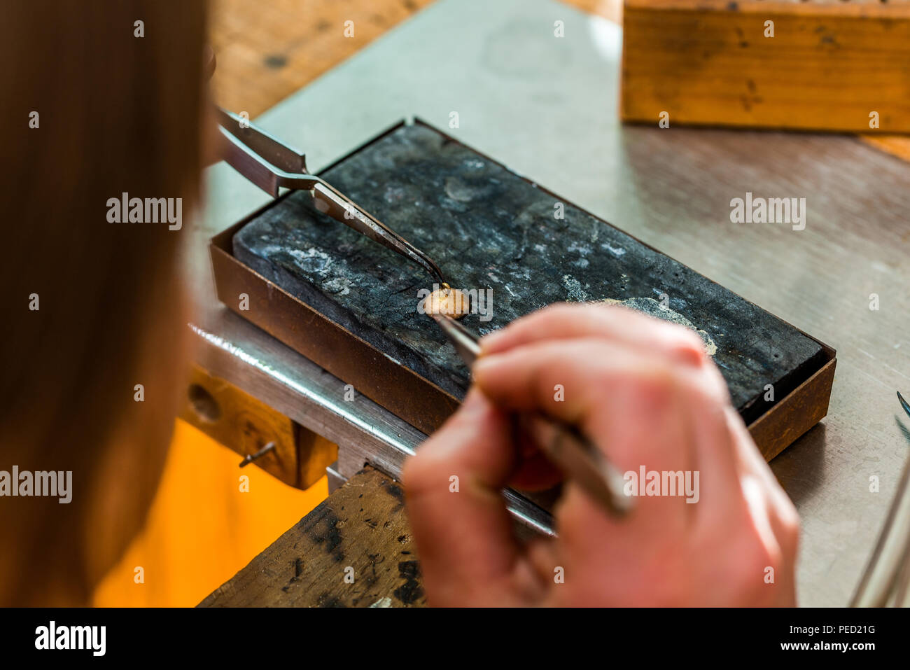Goldsmith working and soldering an unfinished jewelry piece with a ...