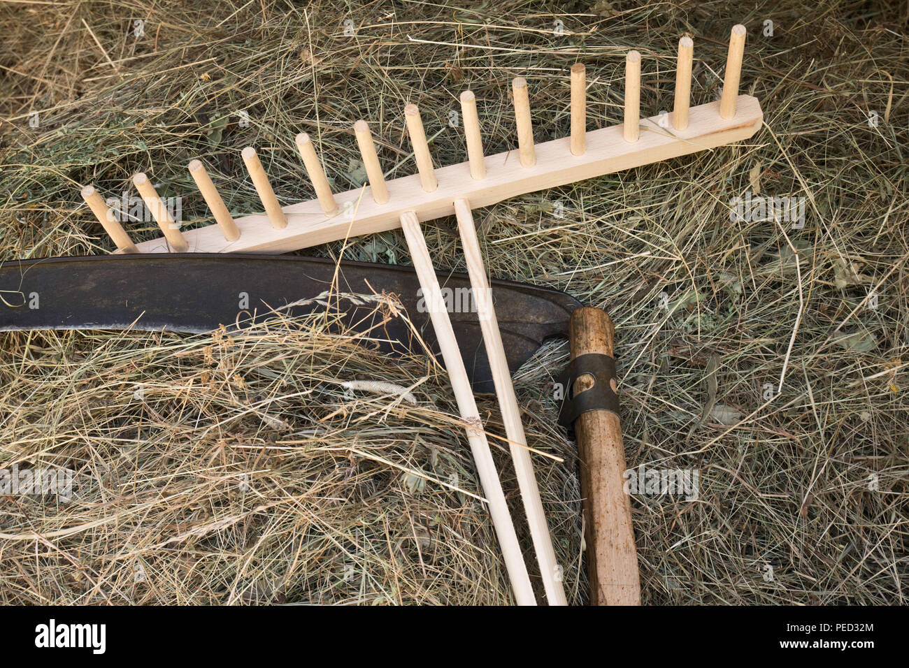 A scythe and a rake with hay Stock Photo - Alamy
