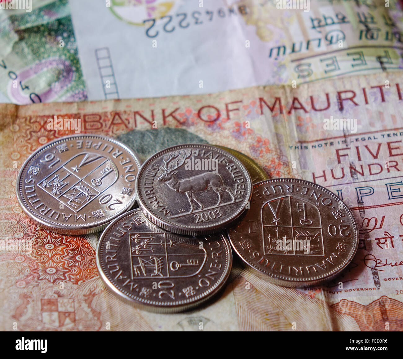 Mauritius Rupee (MUR) notes and coins with red background - close up ...