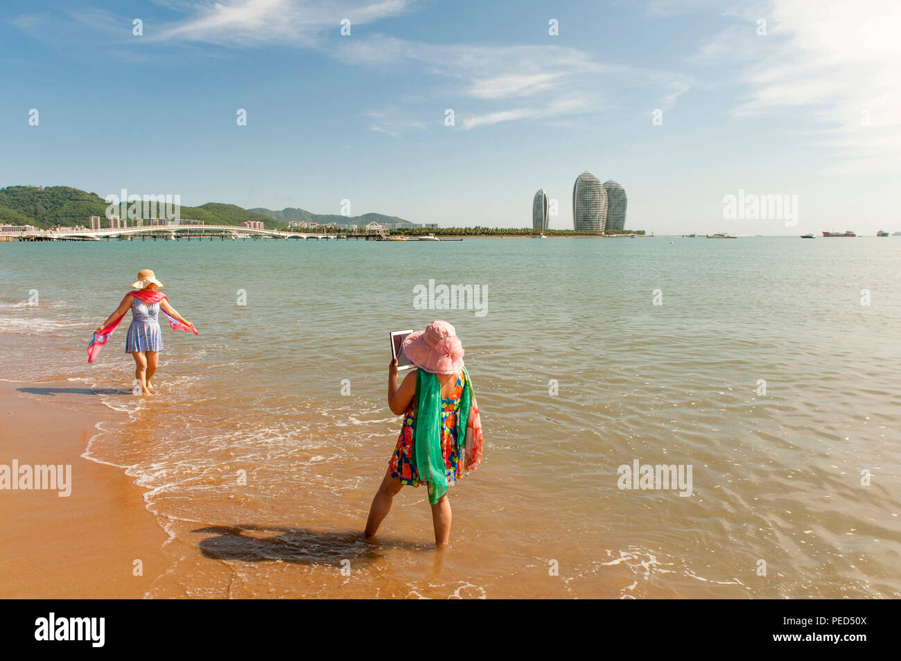Two Chinese ladies taking pictures of each other at the public beach of ...