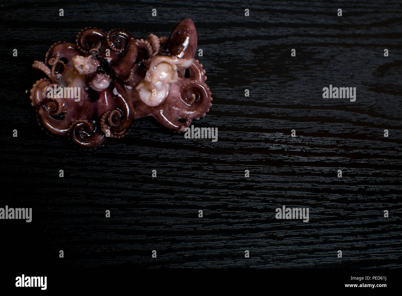 Raw octopus in oil isolated on black table, ready to eat. Seafood. Top ...