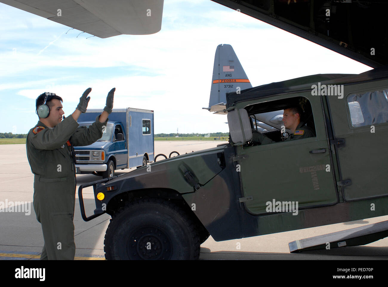 A loadmaster with the 169th Airlift Squadron, marshals a Humvee down a ...