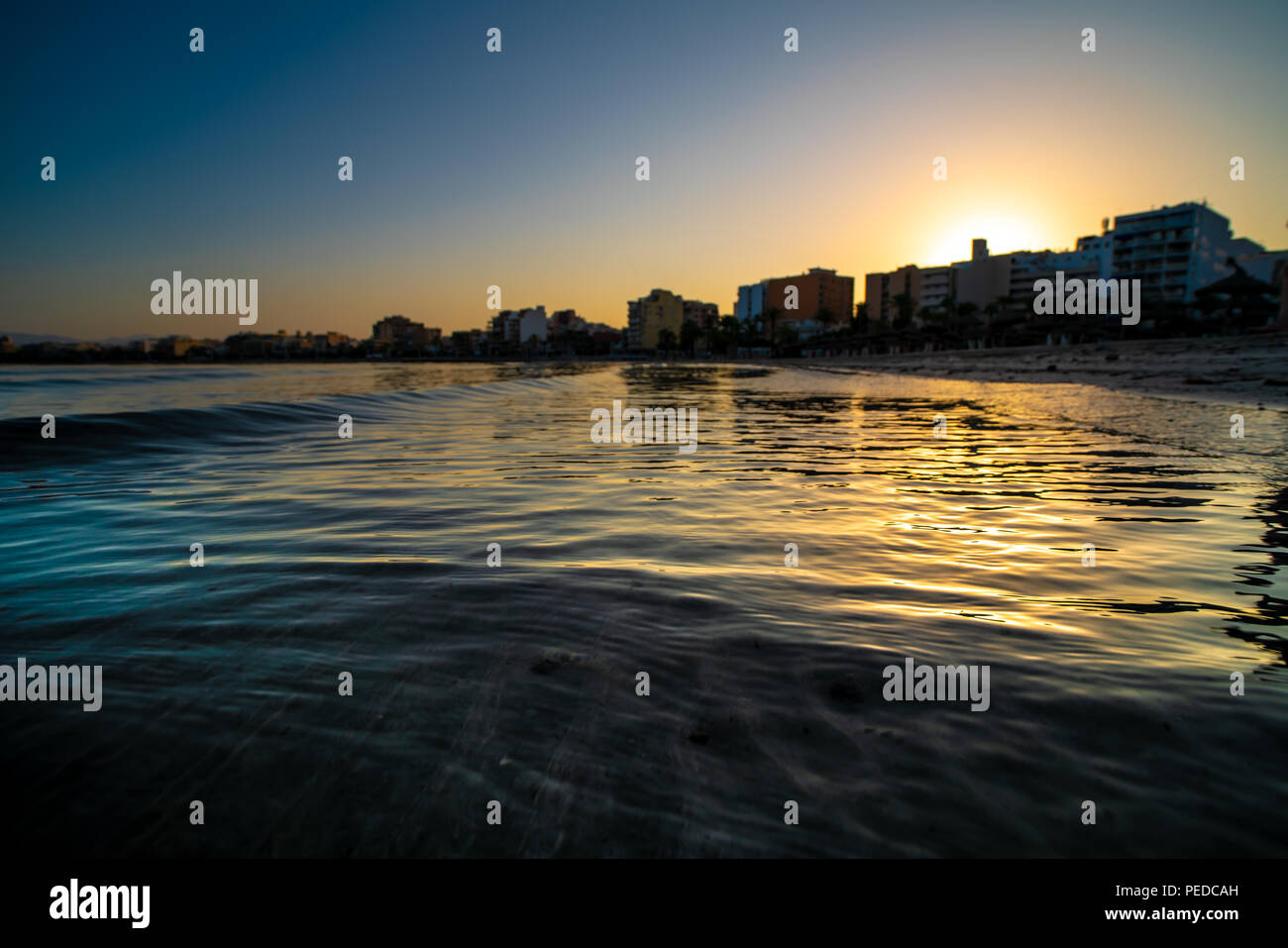 Wavy curves of sea is covered in golden sunset light. Sea at sunset ...