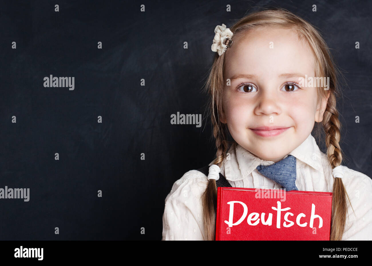 Kids learn German. Curious child girl with german book on chalkboard in ...