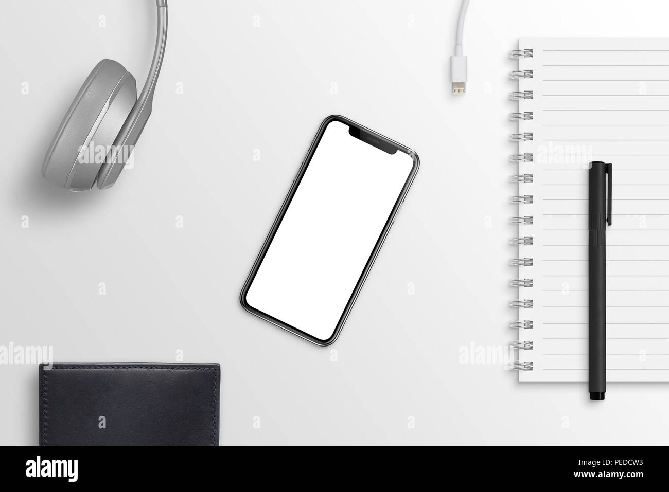 Smart phone on office desk surrounded with headphones, pad, pencil ...