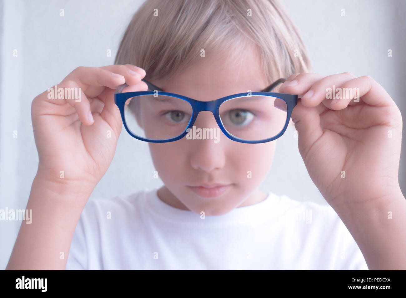 Kid holding glasses and looking through it Stock Photo - Alamy