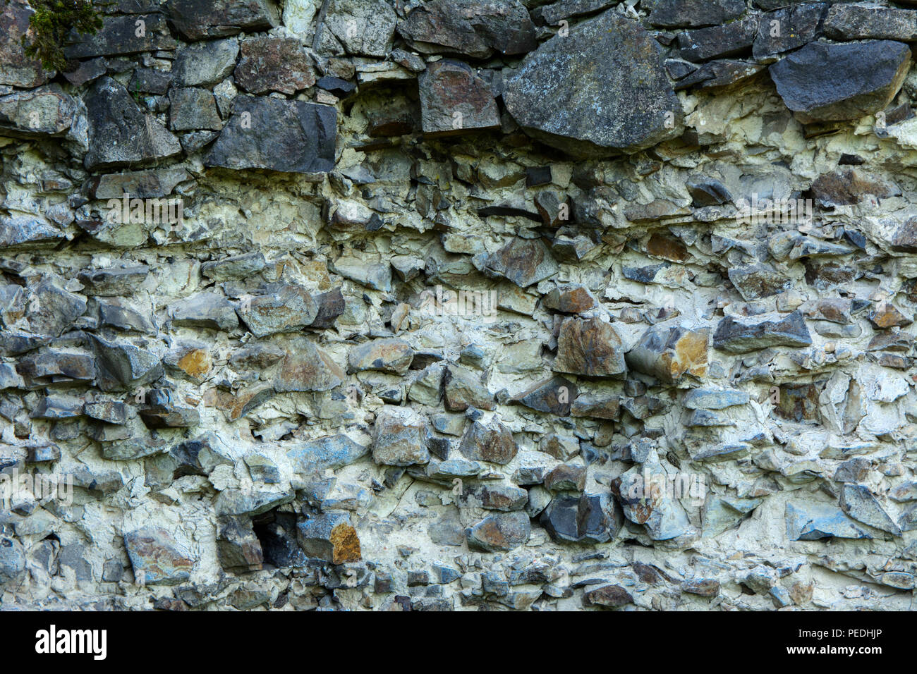 An old faded stone in the cracked weathered and shattered wall of a ...