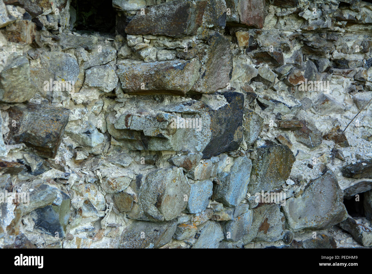 An old faded stone in the cracked weathered and shattered wall of a ...