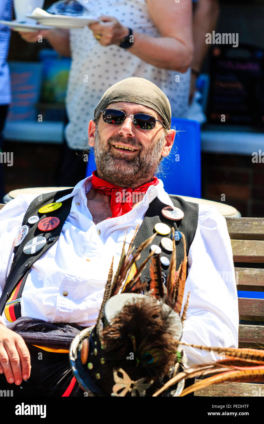 Traditional English folk dancer, morris man, laying back on bench ...