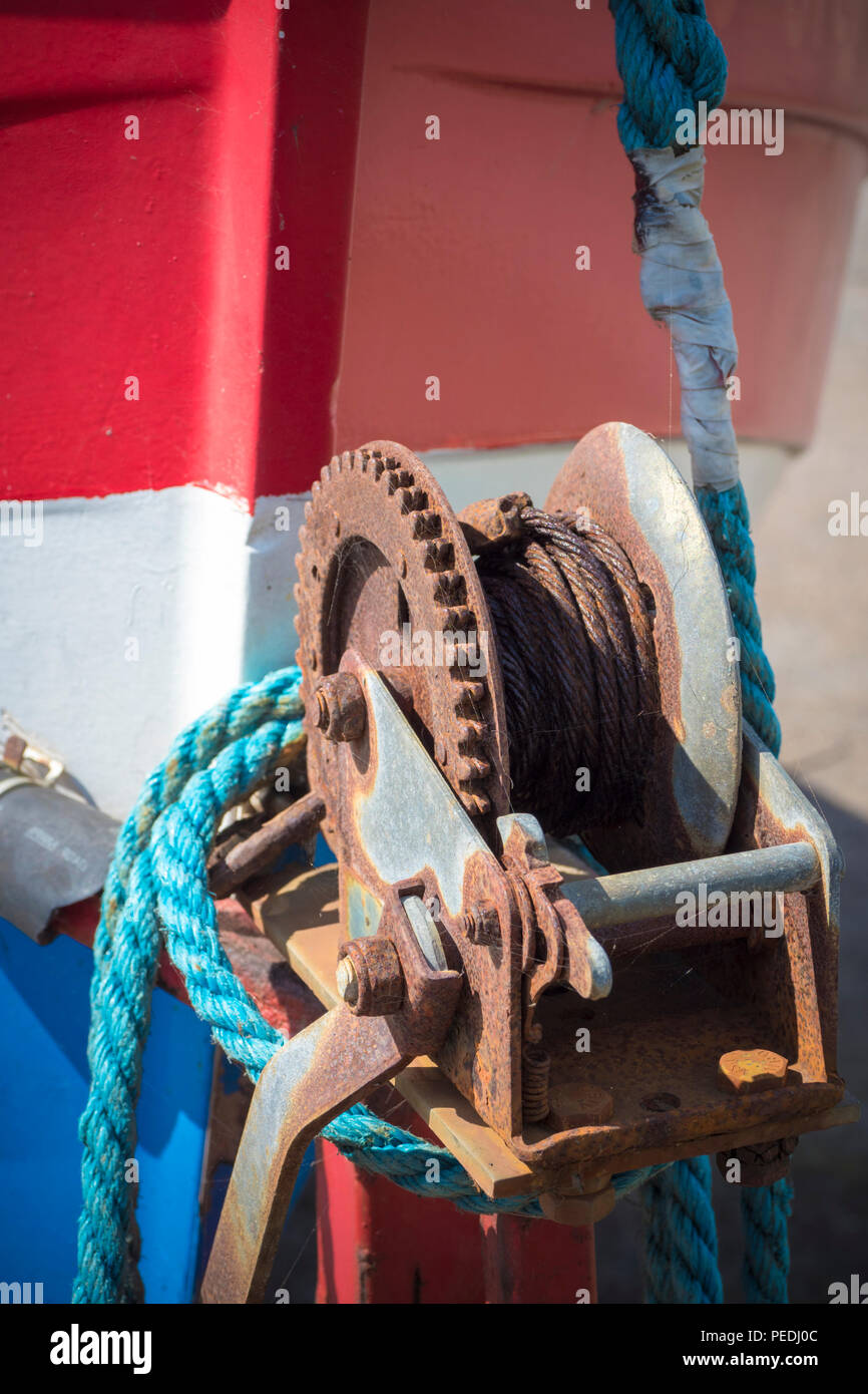 A rusty winch on the trailer of a red, white, and blue painted fishing ...