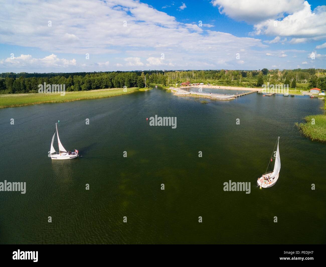 Aerial view of yachts sailing on Mamry Lake, concrete quay and town ...