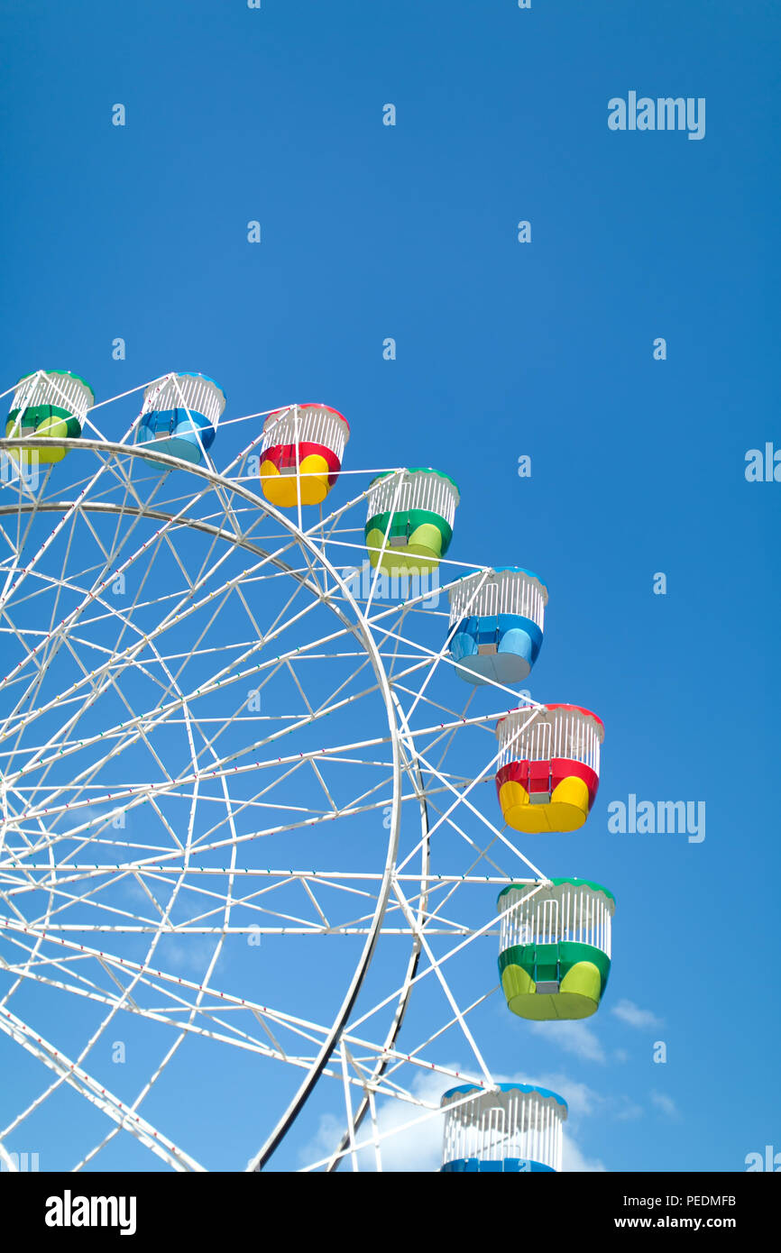A brightly coloured Ferris wheel (big wheel) against a clear blue sky ...