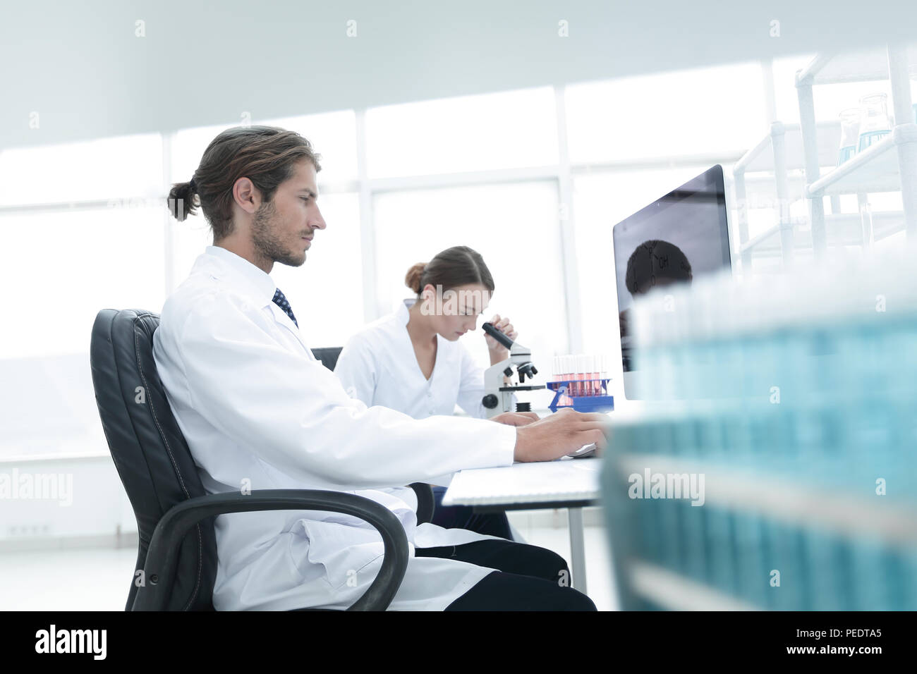 Scientist looking at specimen while his assistant helping him Stock ...