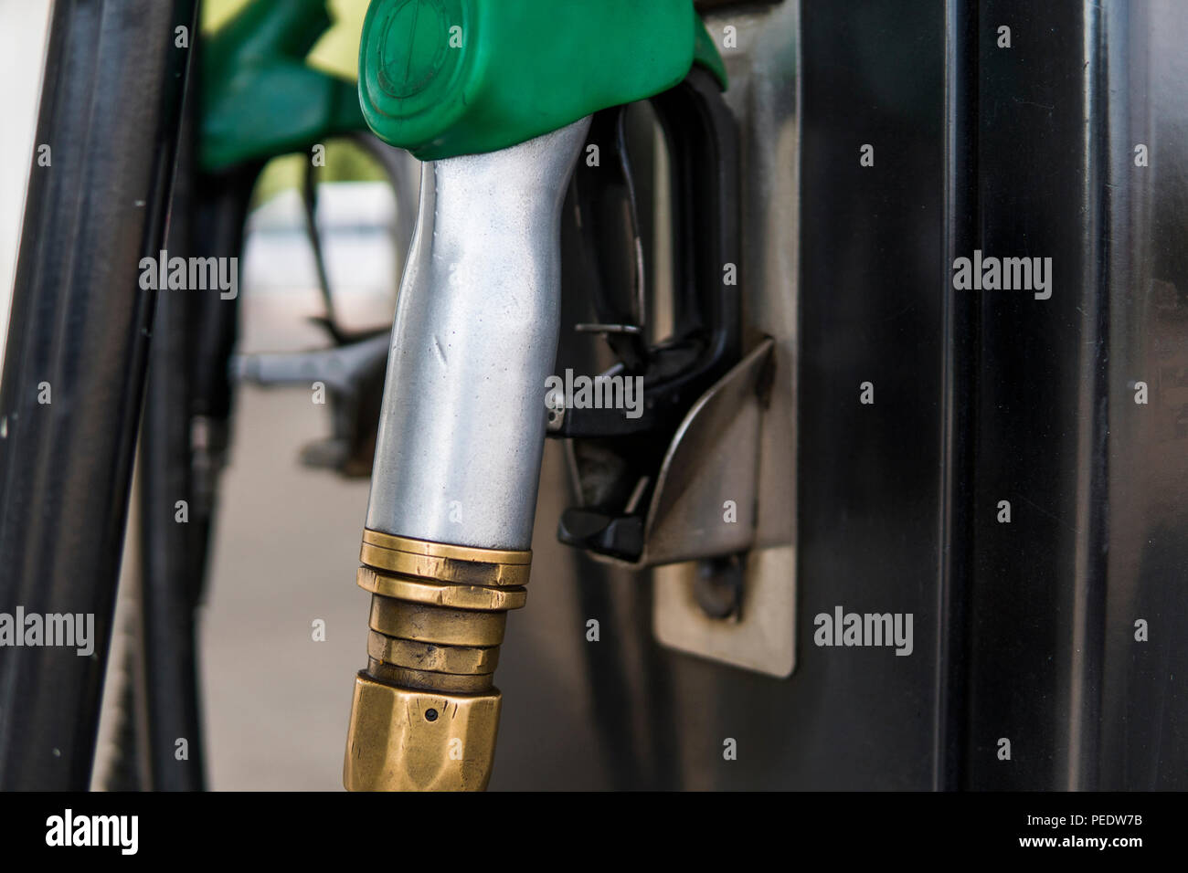Close up on dirty fuel nozzle in oil dispenser with gasoline and diesel ...