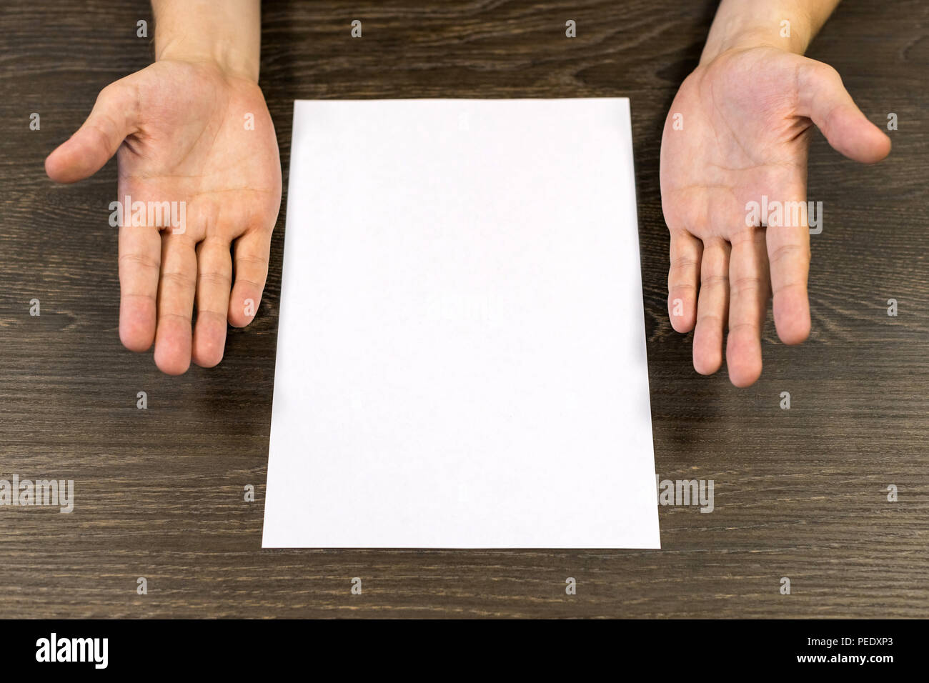 Businessman sitting at table. There are blank sheet of paper on the ...