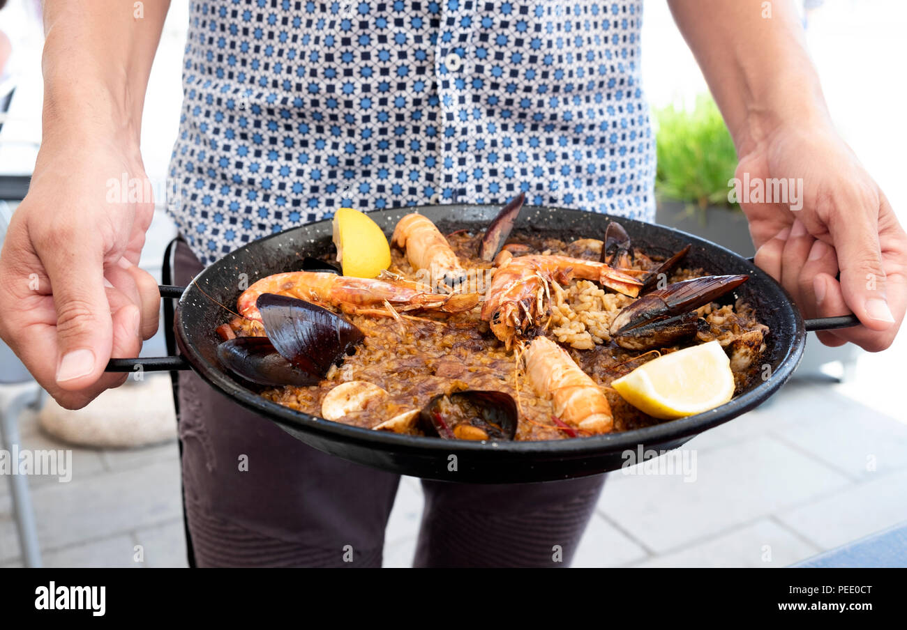 closeup of a young caucasian holding a typical spanish seafood paella ...