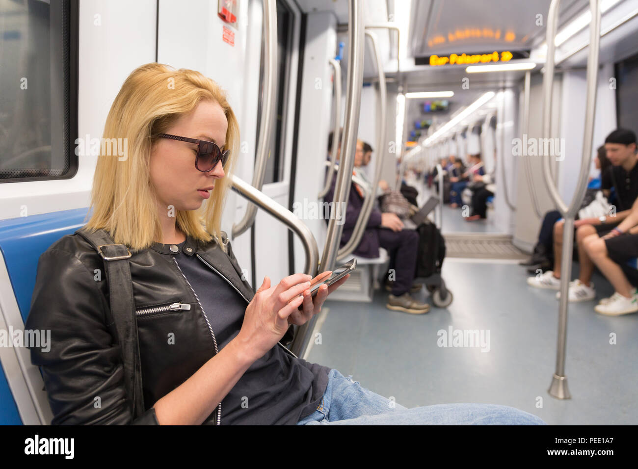 Young girl reading from mobile phone screen in metro Stock Photo - Alamy
