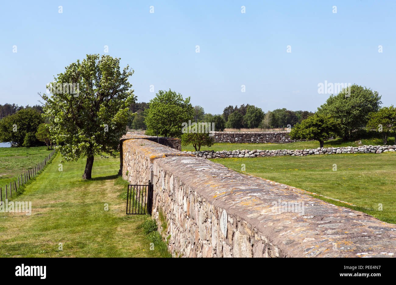 Exterior of a stone wall surrounding a field. A huge wall, gate this ...