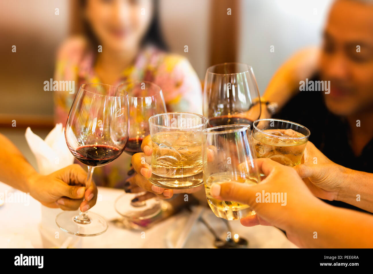 Group of friends raising a toast with glasses of red wine and whiskey ...