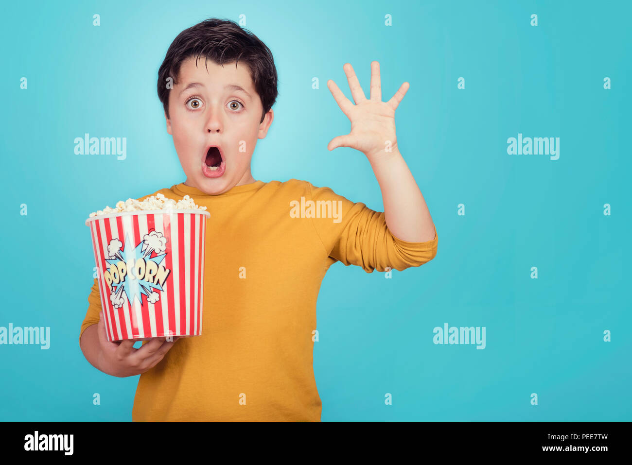surprised child with popcorn on blue background Stock Photo - Alamy