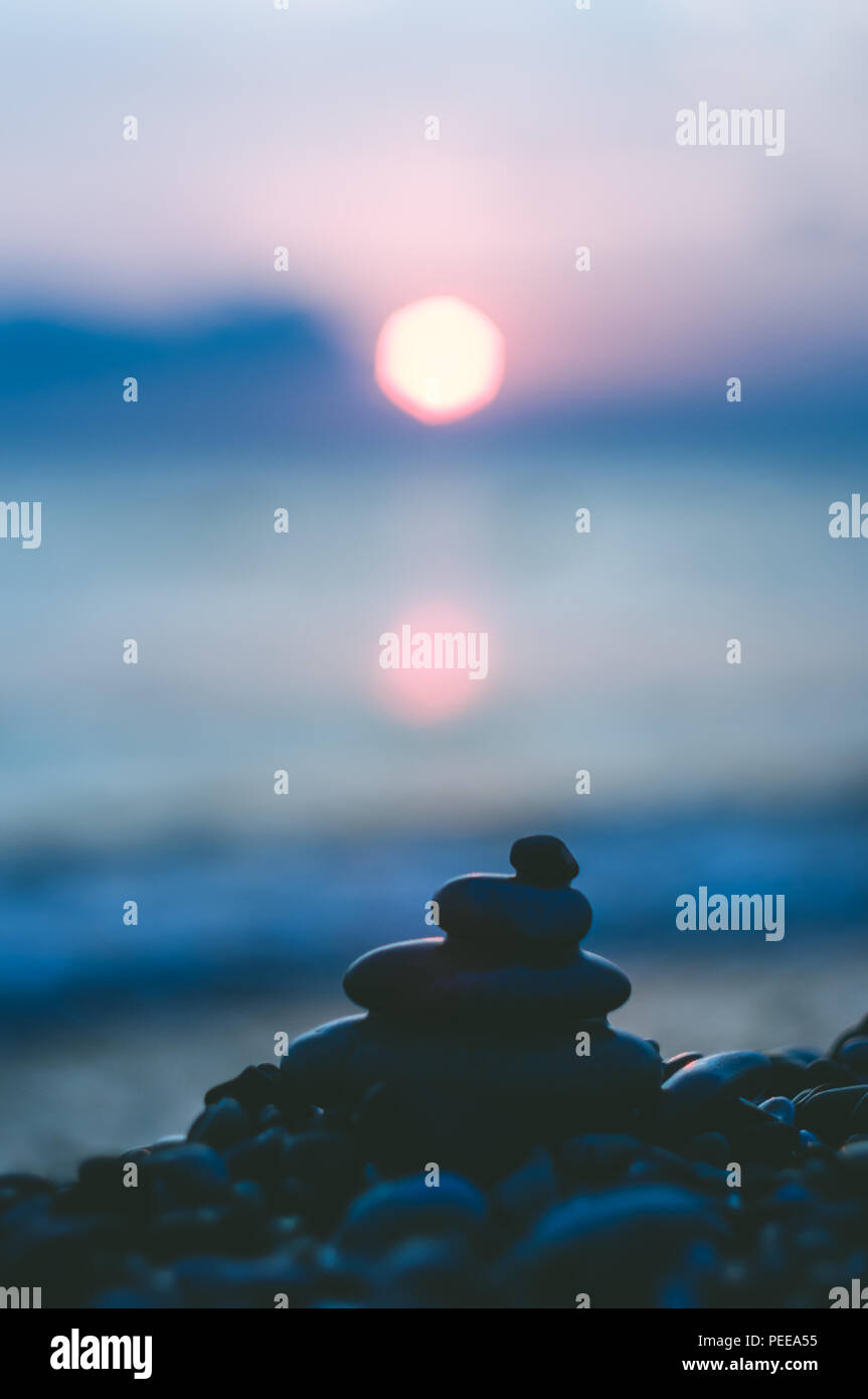folded pyramid Zen pebble stones on the sea beach at sunset Stock Photo ...
