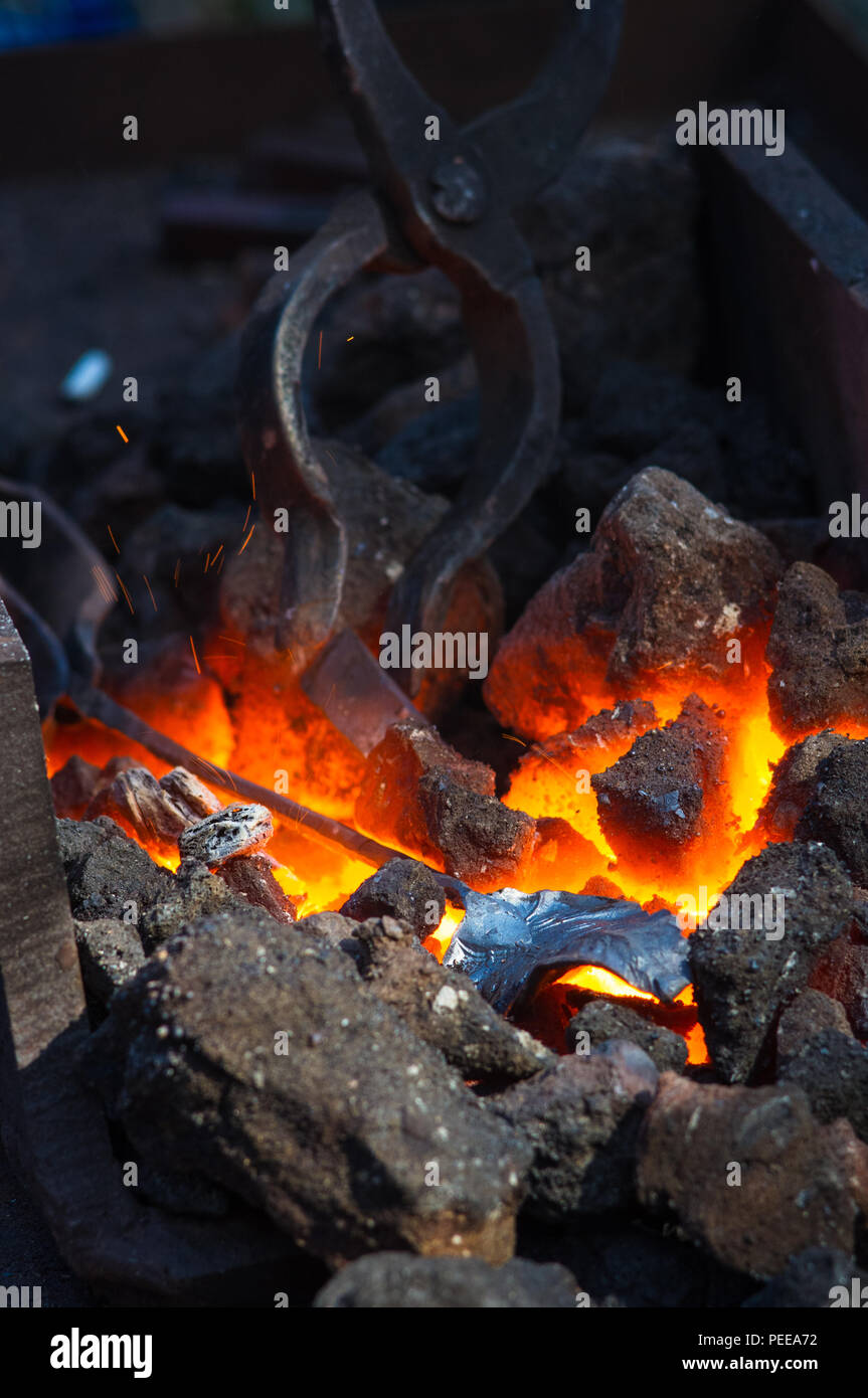 blacksmith furnace with burning coals, tools, and glowing hot metal ...