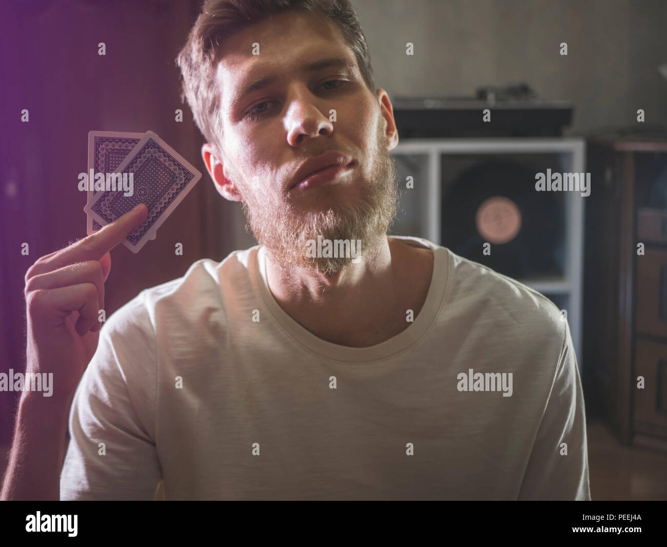 portrait of bearded young man holding playing cards to make a trick in ...