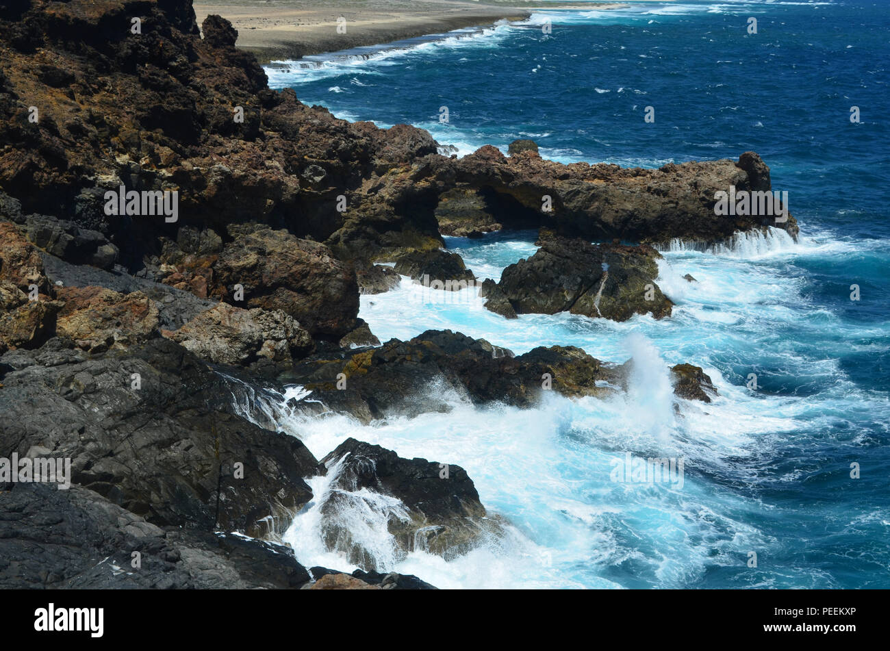 Rugged lava rocks with waves splashing onto them in Aruba Stock Photo ...