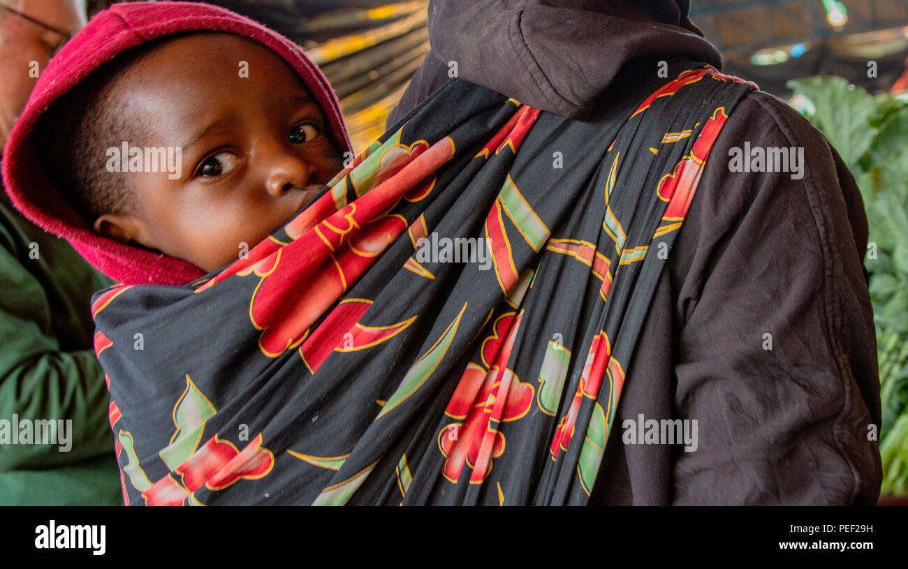 Windhoek, South Africa / July 6, 2018: Baby is carried on mother's back ...