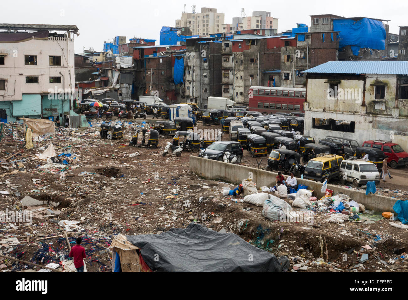 Slum area covered in trash with tuk tuk auto rickshaws waiting for ...
