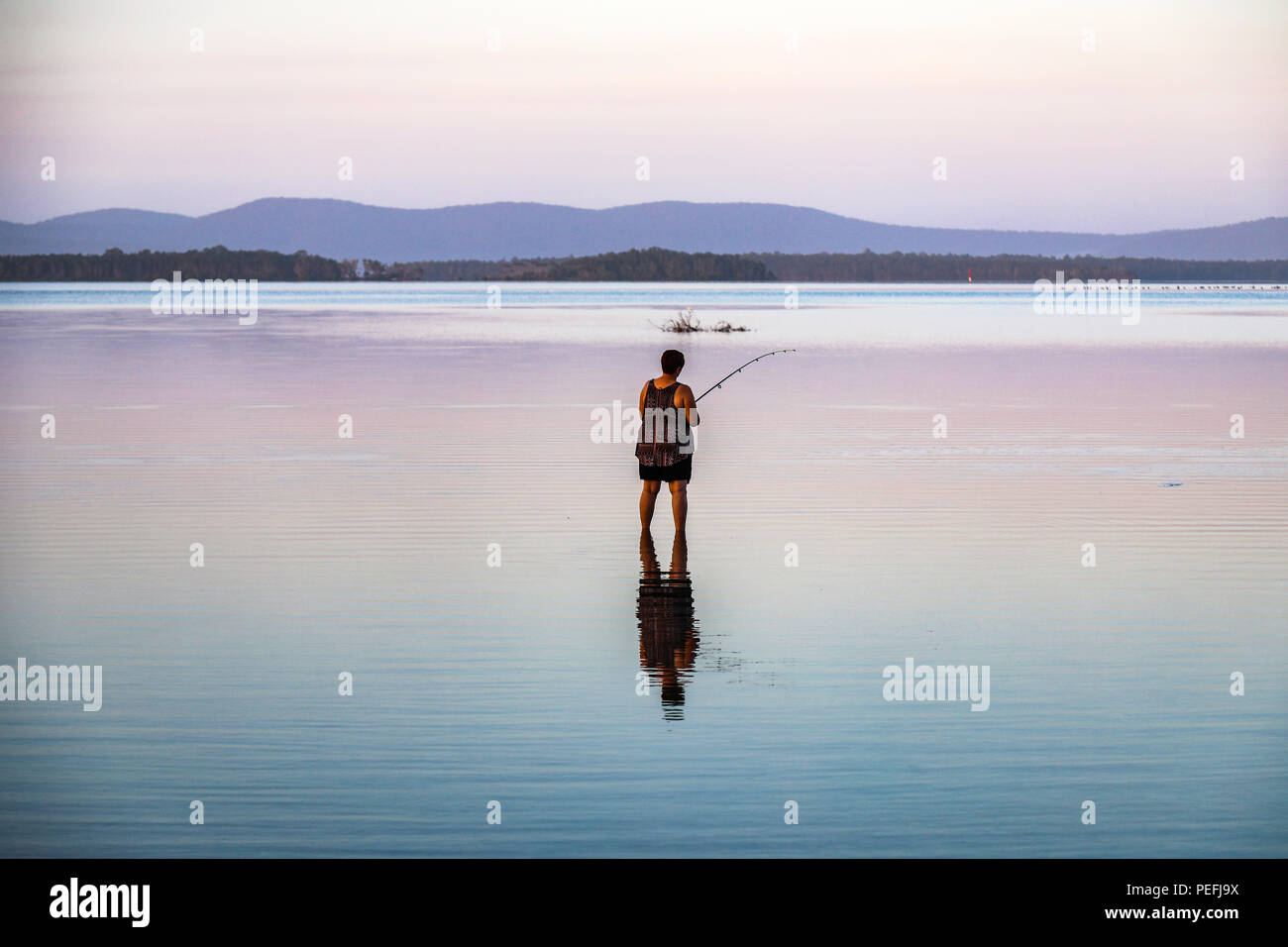 Person fishing on lake with reflection Stock Photo - Alamy
