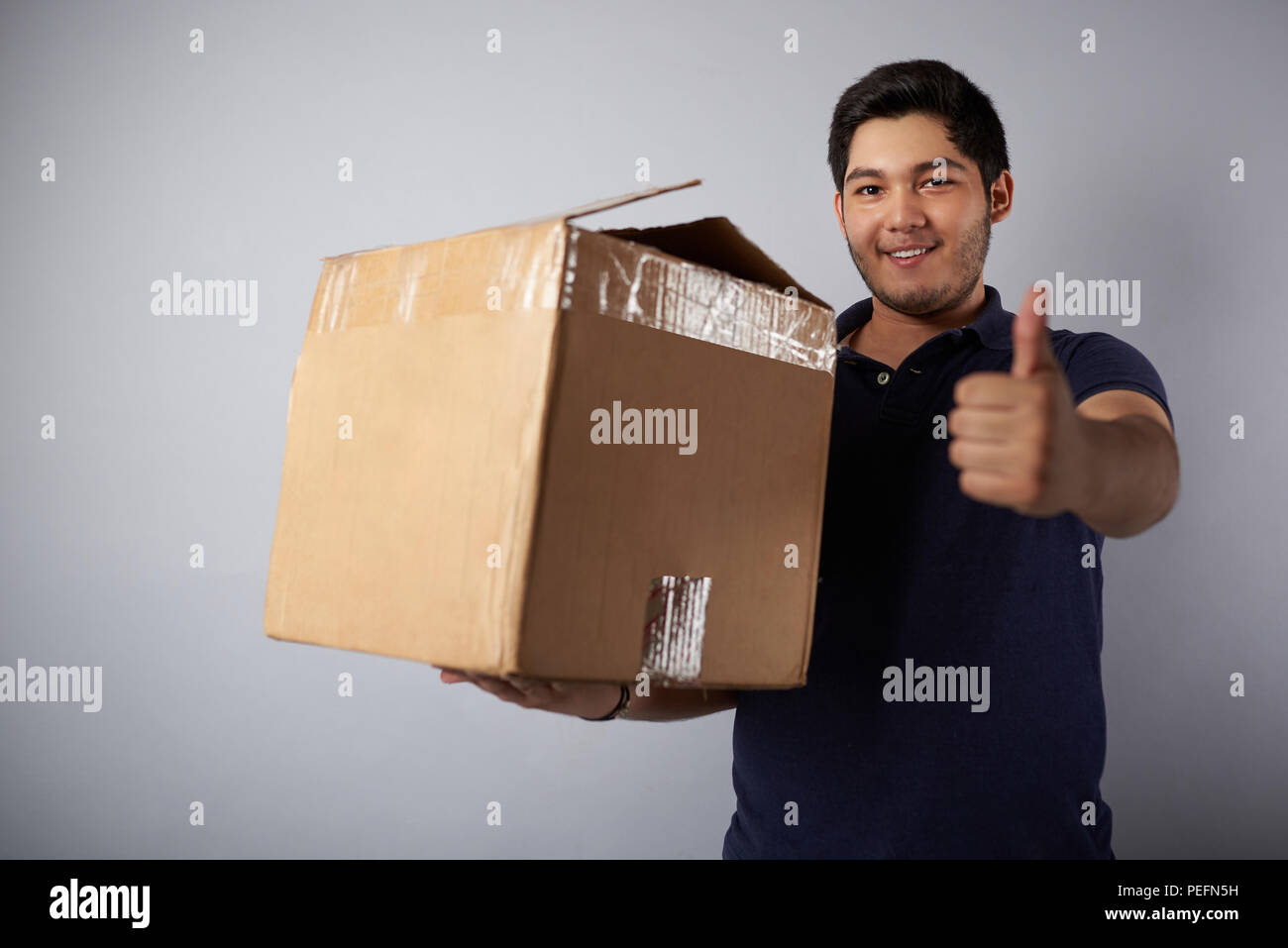 Young man with delivered box show thumb up Stock Photo - Alamy