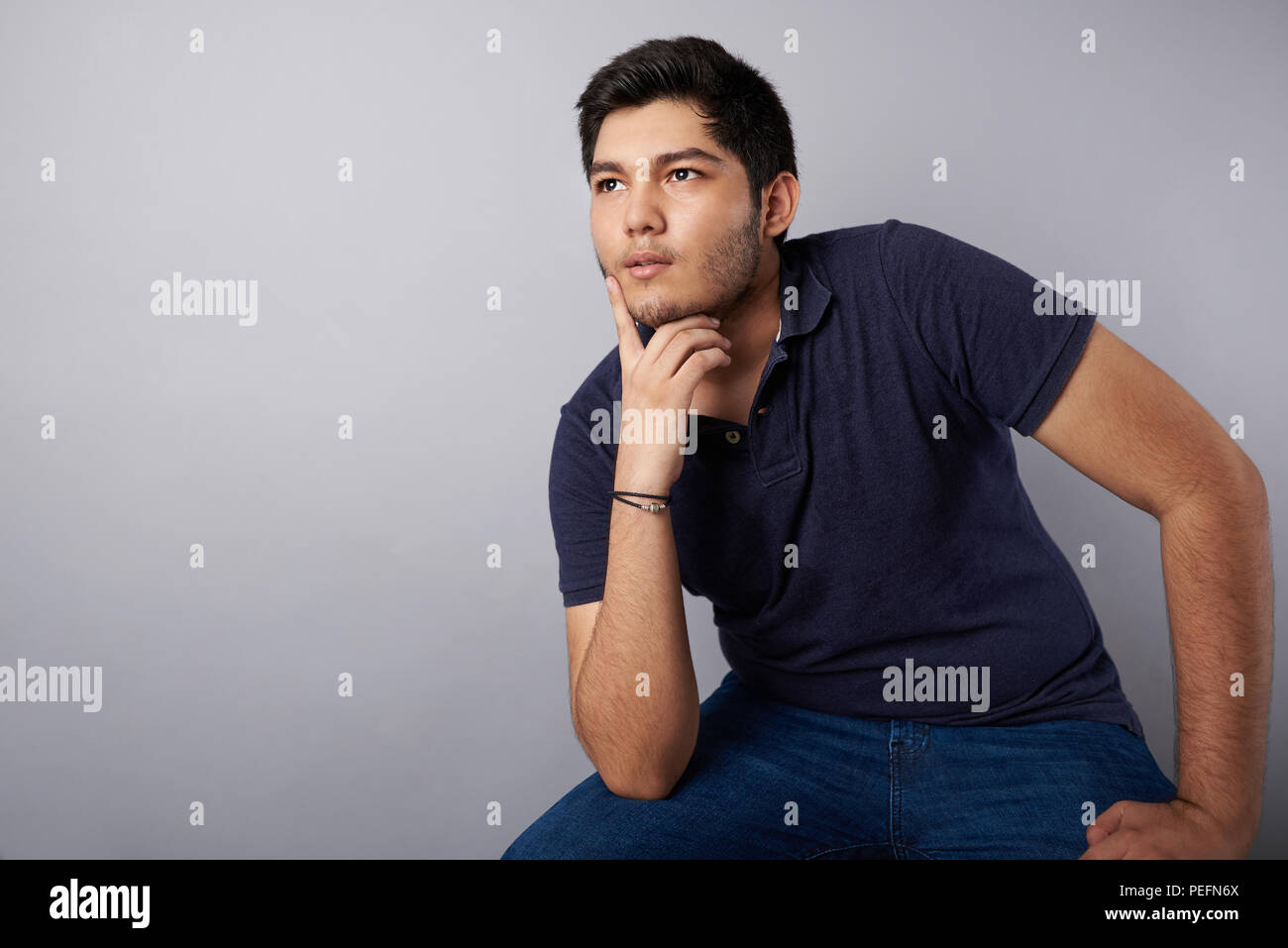 Thinking young man portrait with copy space on gray studio background ...