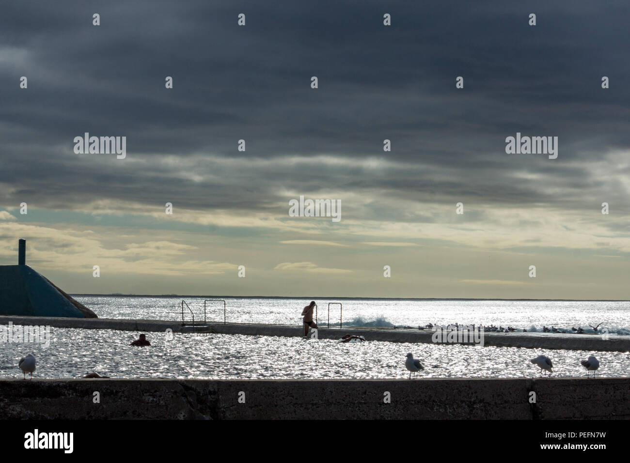 Swimmers at ocean baths beneath stormy sky Stock Photo - Alamy