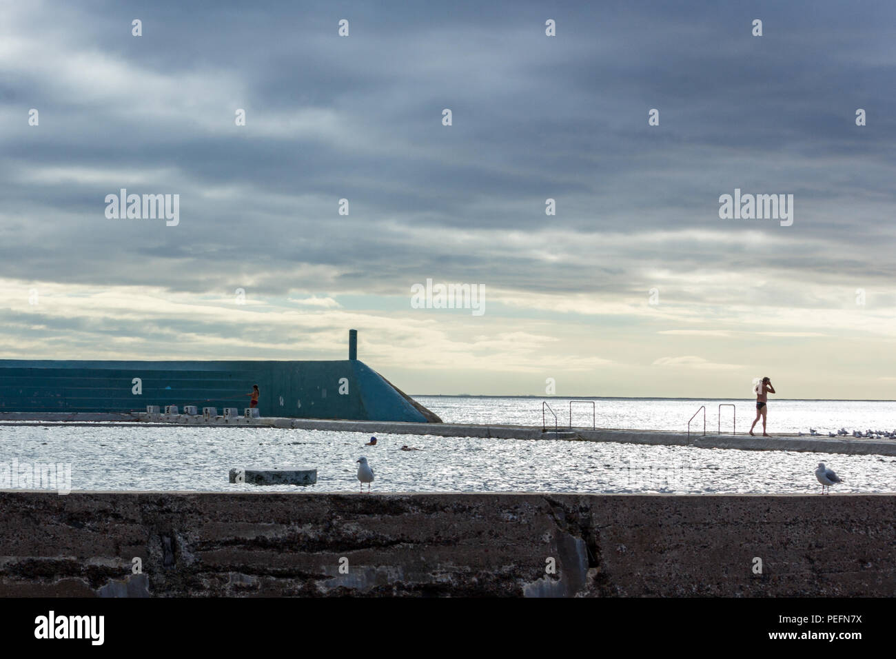 Swimmers at ocean baths beneath stormy sky Stock Photo - Alamy