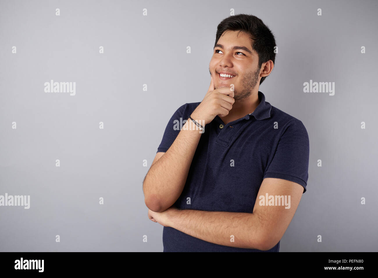 Happy smiling young man thinking on gray studio background Stock Photo ...