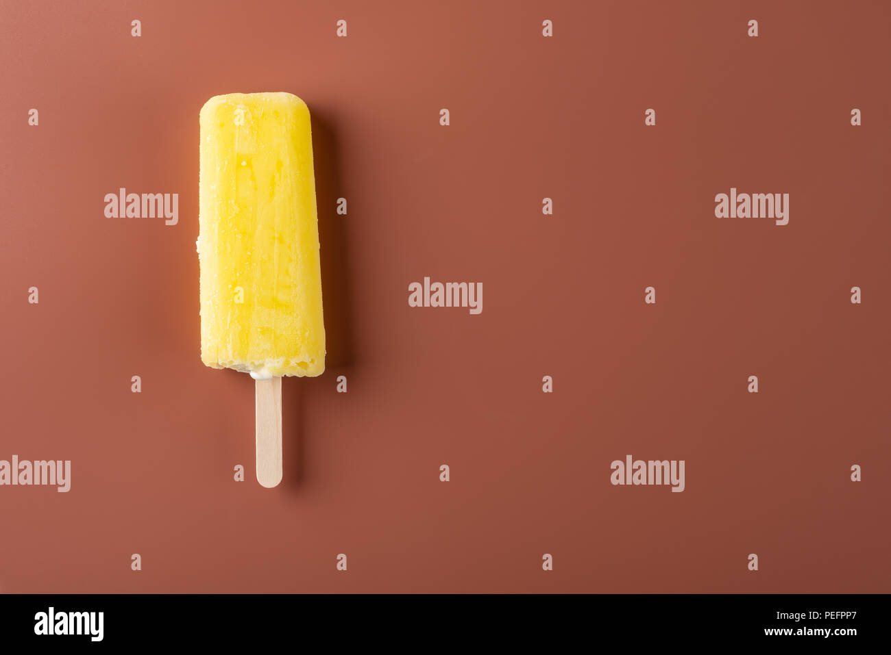 yellow popsicle on a chocolate brown background Stock Photo - Alamy