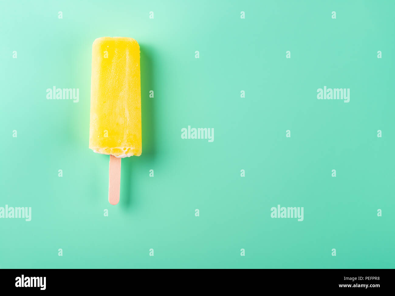 yellow popsicle on a light green background Stock Photo - Alamy