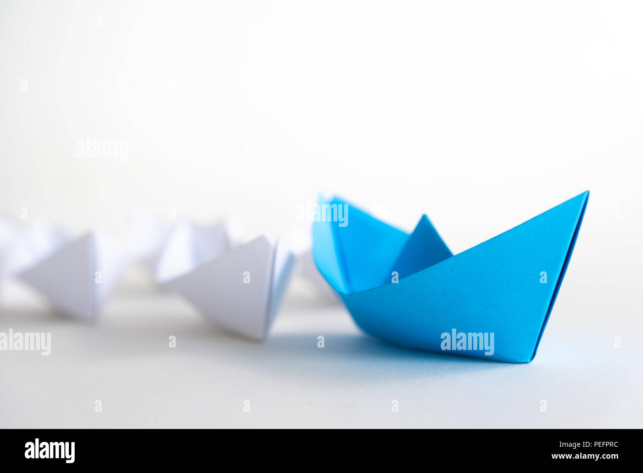Leadership concept. blue paper ship lead among white. One leader ship ...
