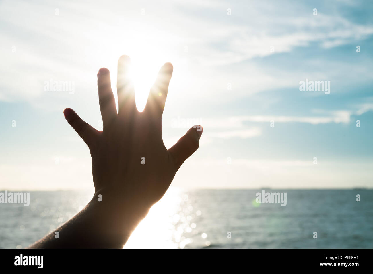 Hand touching sun during sunset background success, peace, freedom and ...