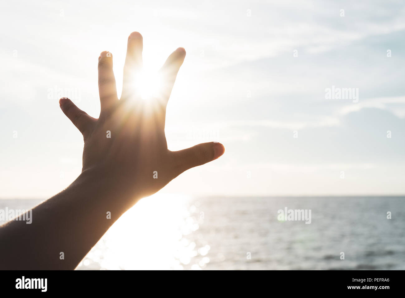 Hand touching sun during sunset background success, peace, freedom and ...