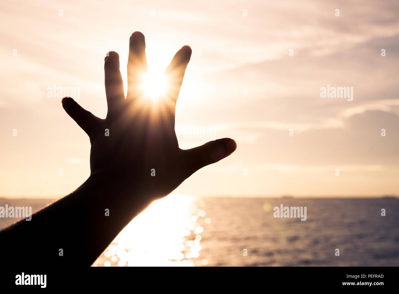 Hand touching sun during sunset background success, peace, freedom and ...