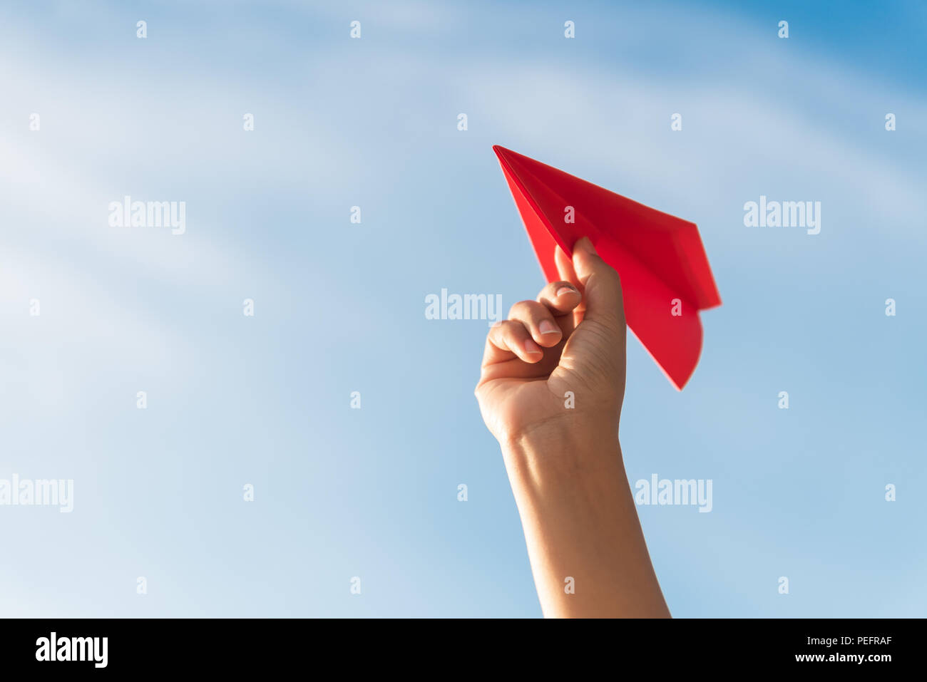 Woman Hand holding red paper rocket with blue sky background. freedom ...