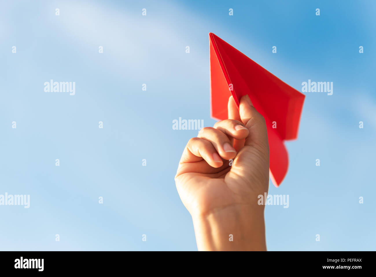 Woman Hand holding red paper rocket with blue sky background. freedom ...