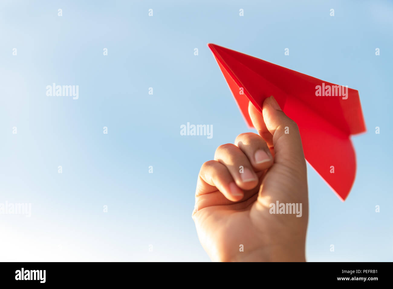 Woman Hand holding red paper rocket with blue sky background. freedom ...