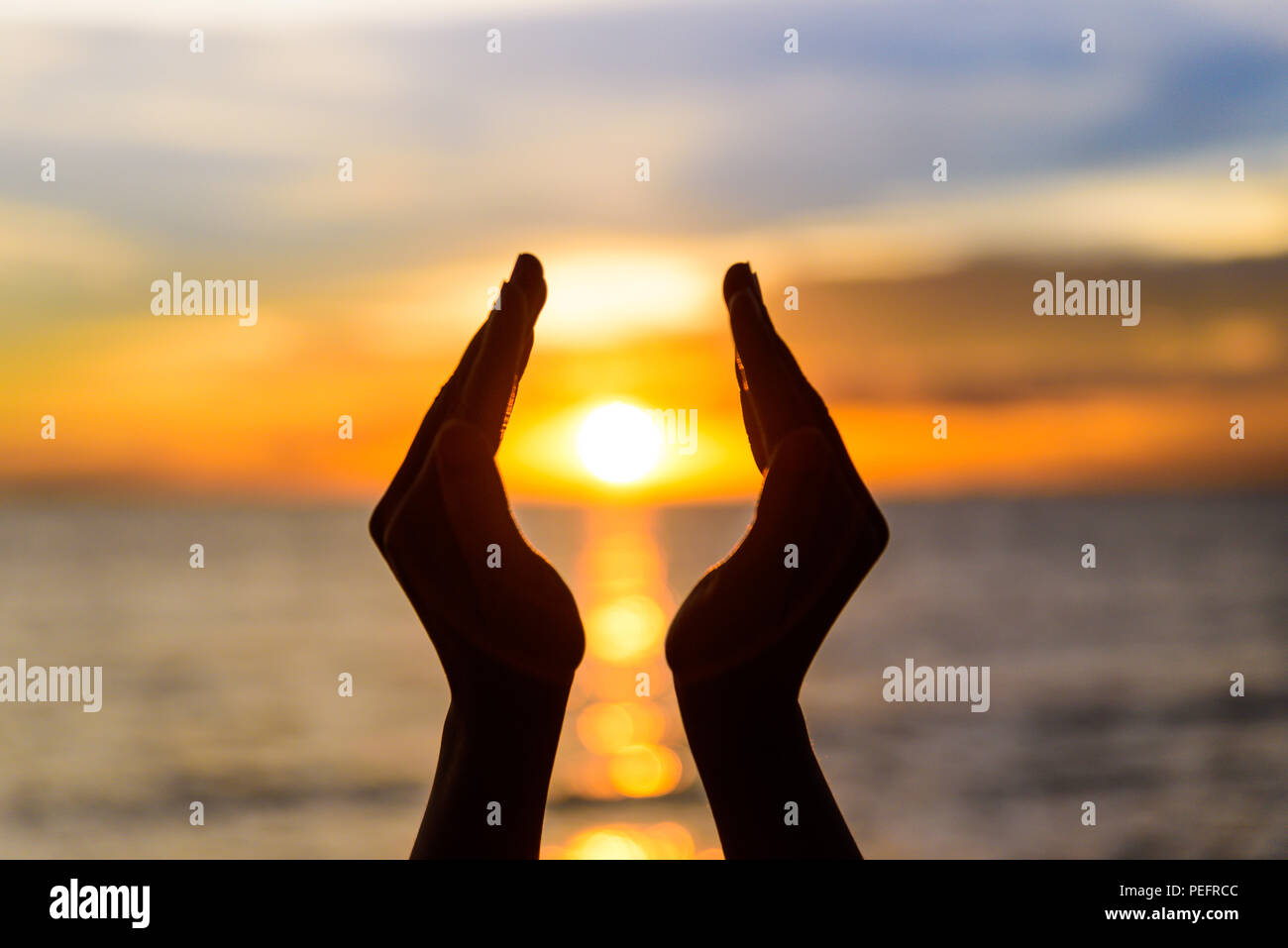 Woman hands holding the sun during sunrise or sunset Stock Photo - Alamy