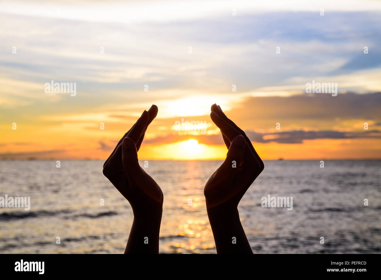 Woman hands holding the sun during sunrise or sunset Stock Photo - Alamy