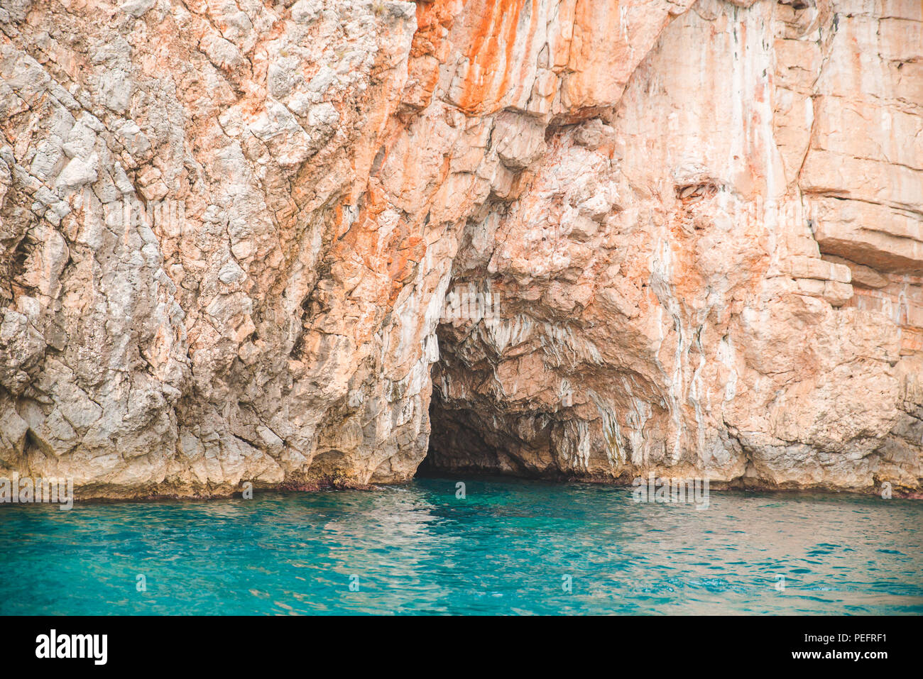 view of grotto in rocky cliff with azure water. summer vacation concept ...