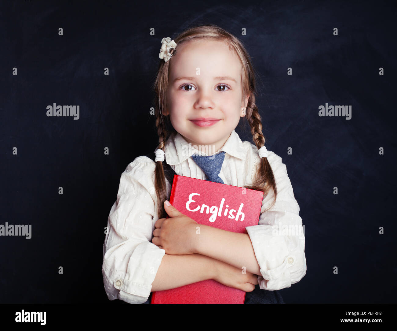 Little child girl embracing english book against chalkboard background ...