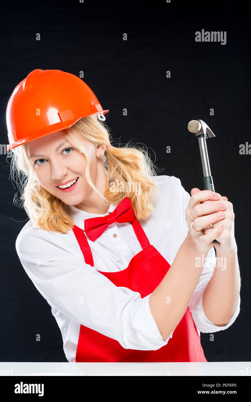 Vertical portrait of a charming chef in helmet with a hammer on a black ...